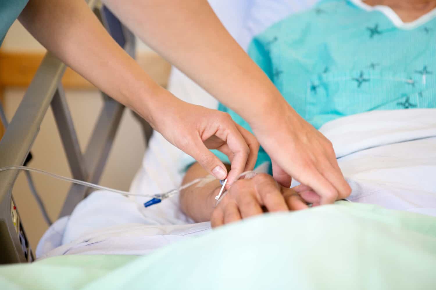 Nurse Attaching IV Drip On Male Patient's Hand - Aquacure Nurse Attaching IV Drip On Male Patient's Hand - Aquacure